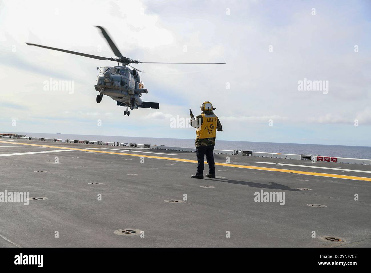 241124-N-IL330-1263 A Sailor guides an MH-60R helicopter attached to ...
