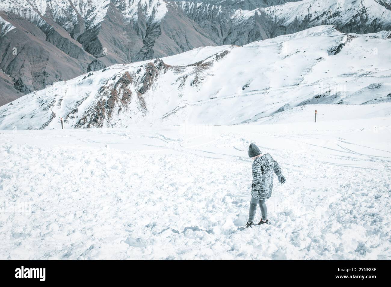 back view of boy child kid in winter coat and beanie in snow fields ...