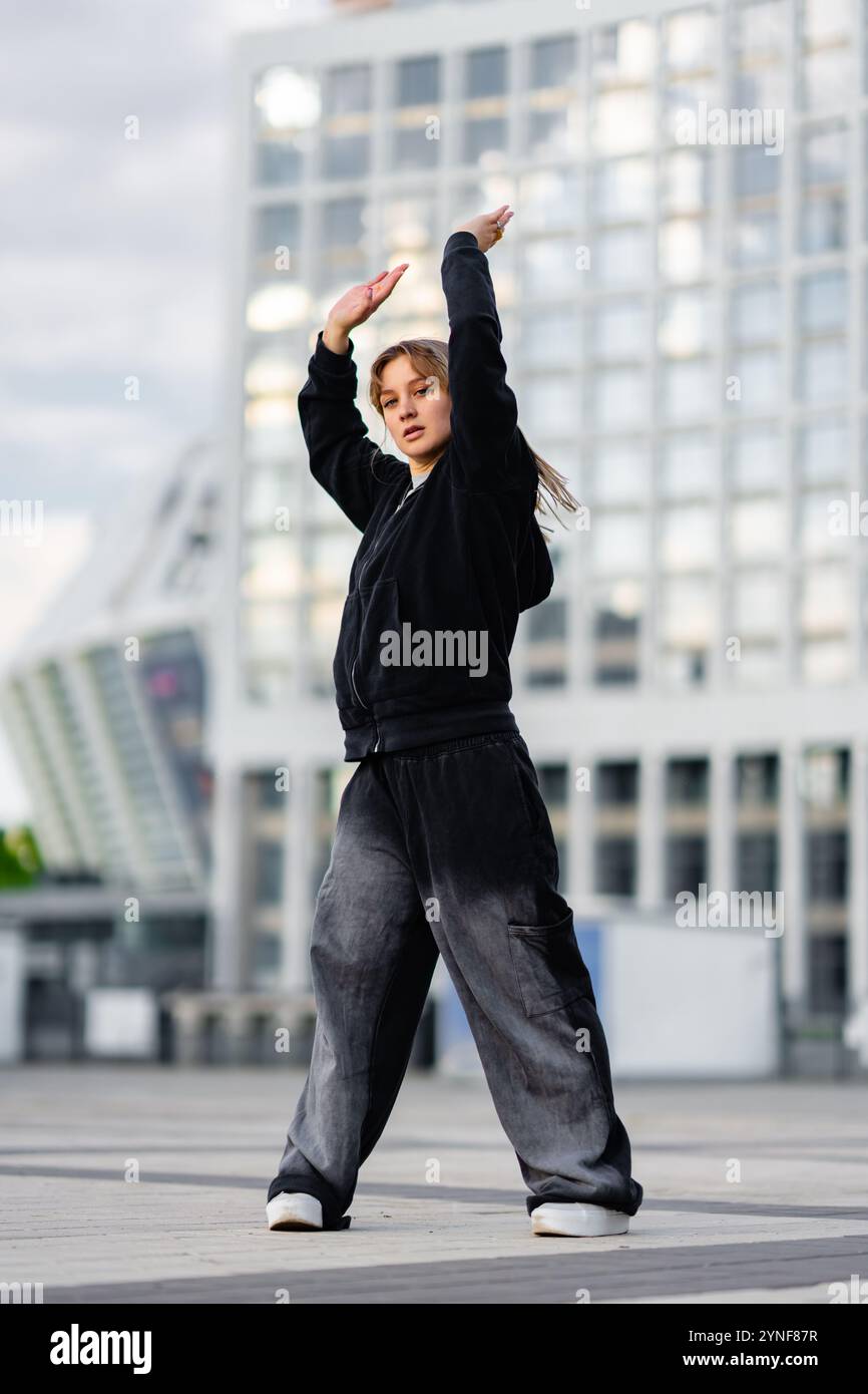 Young woman performing dance moves outdoors in urban setting during ...