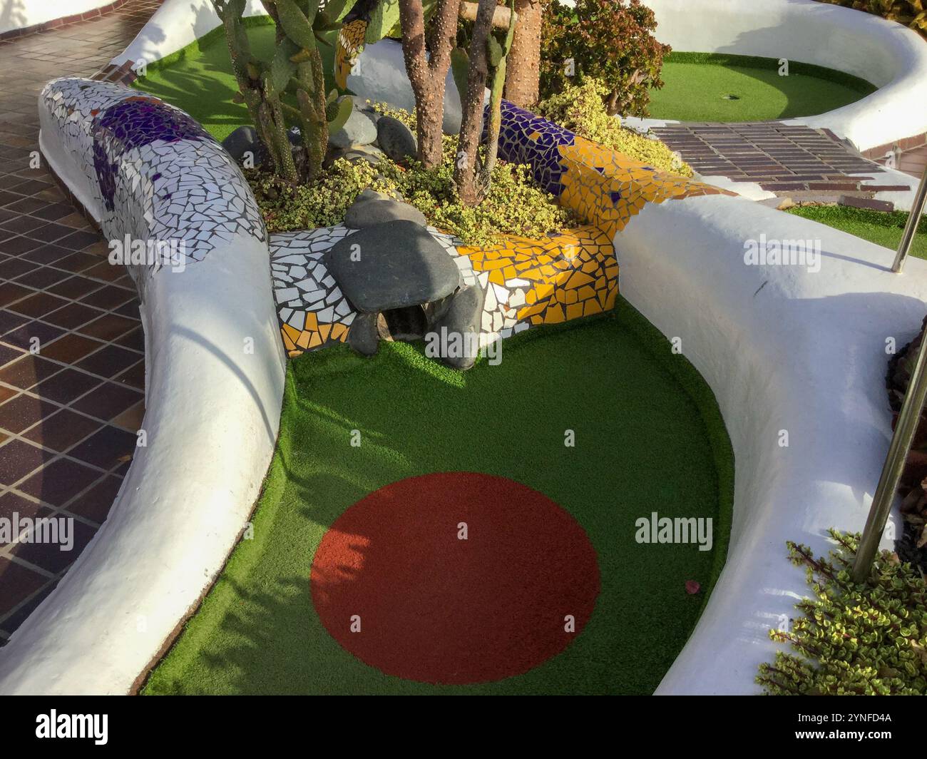 A vibrant mini golf course features unique mosaic designs and lush ...