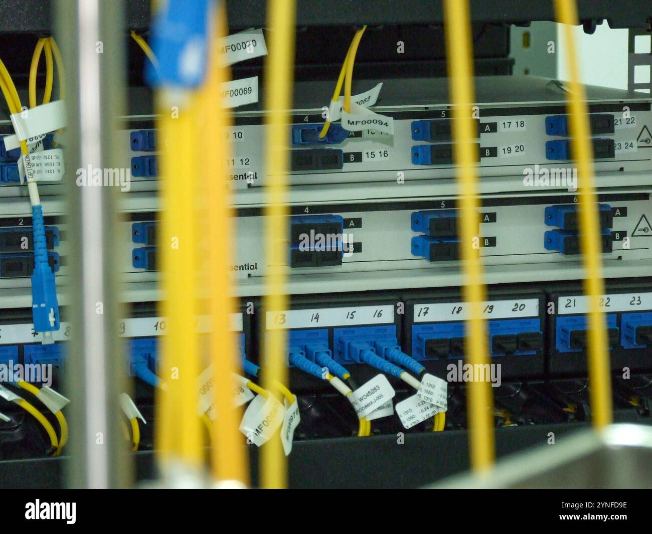 Inside a server room, multiple racks of networking equipment are seen, interconnected by yellow ...