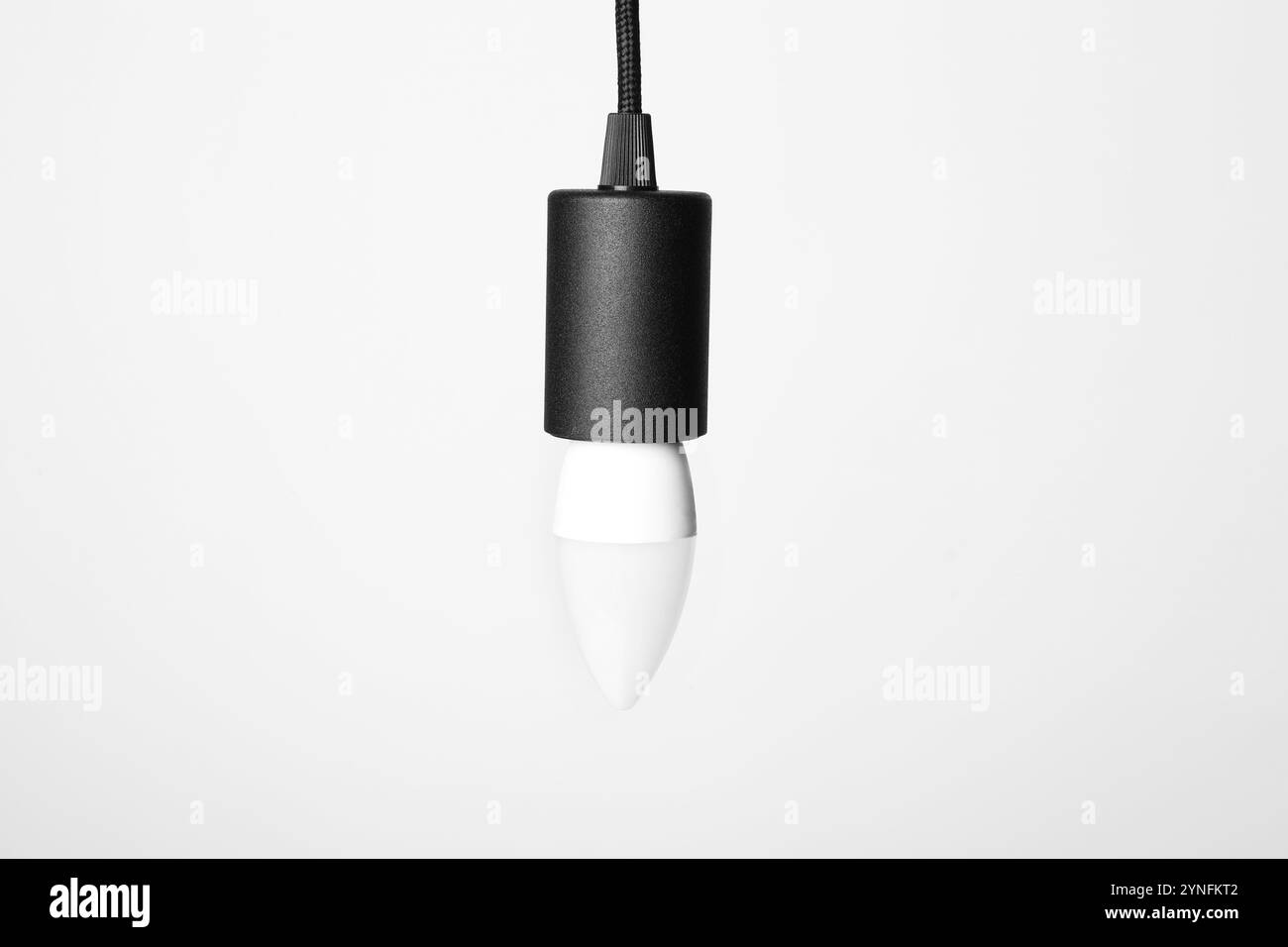 One light bulb hanging on cord against white background Stock Photo - Alamy