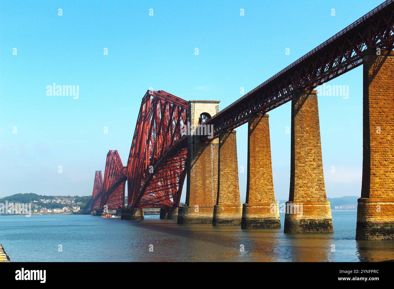 The red steel spans of the historic railway bridge rise over calm ...