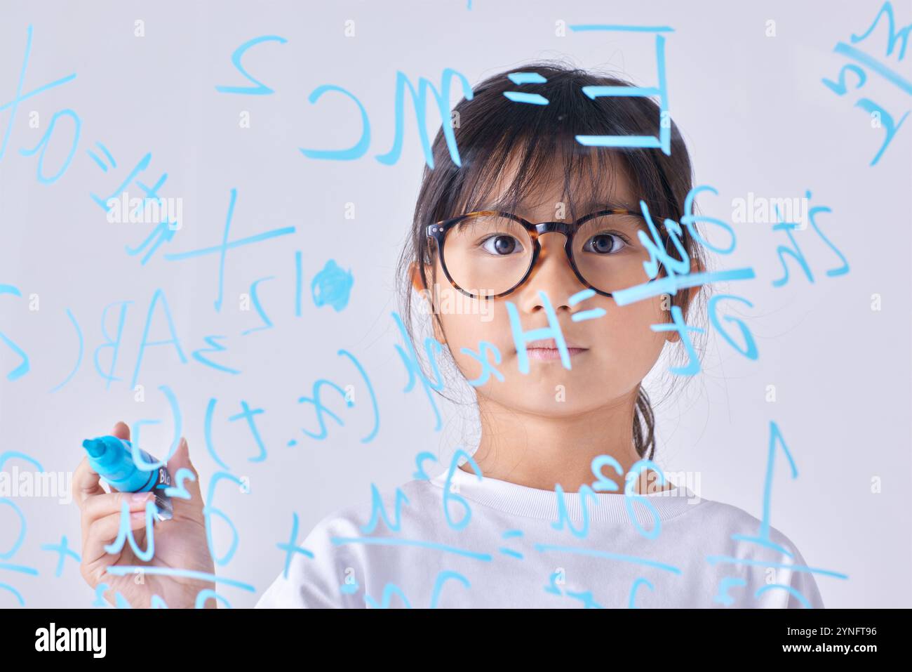 Japanese girl in glasses writing on a white board with math formulas ...