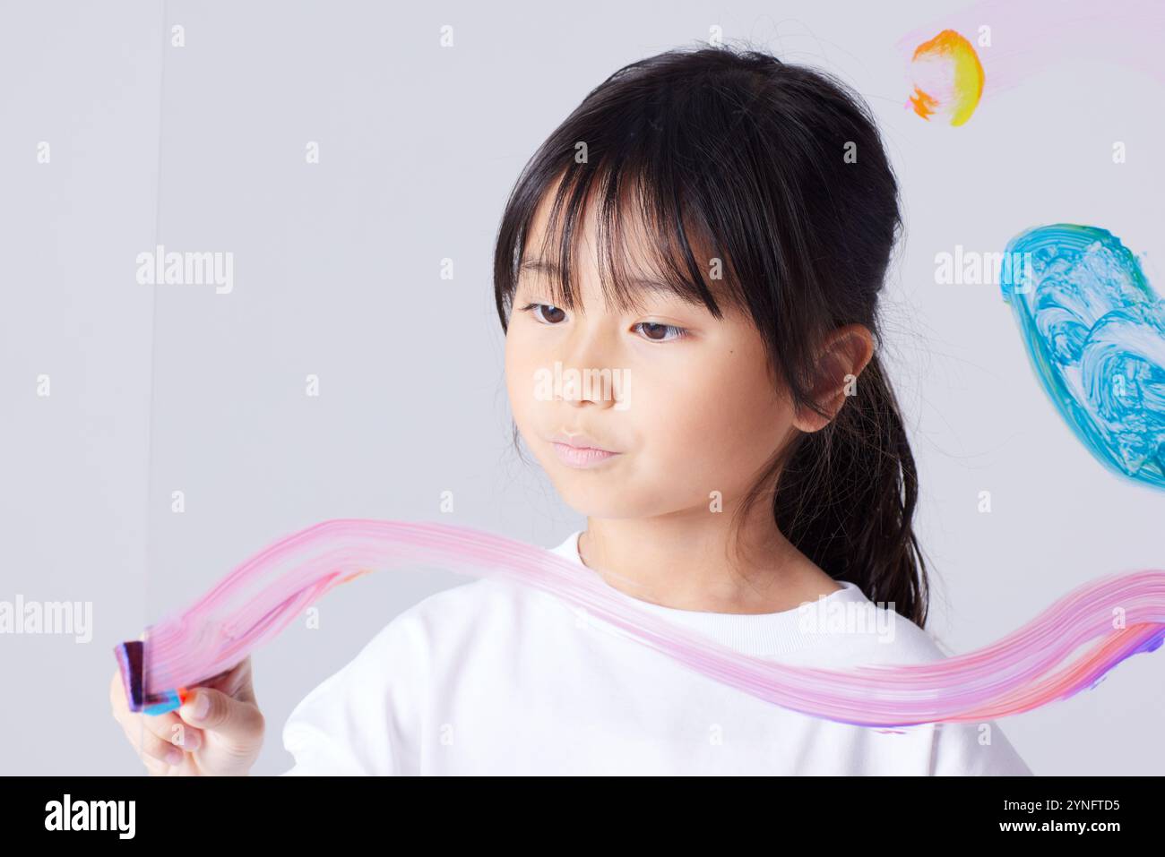 Japanese kid holding a paintbrush and painting on a white background ...