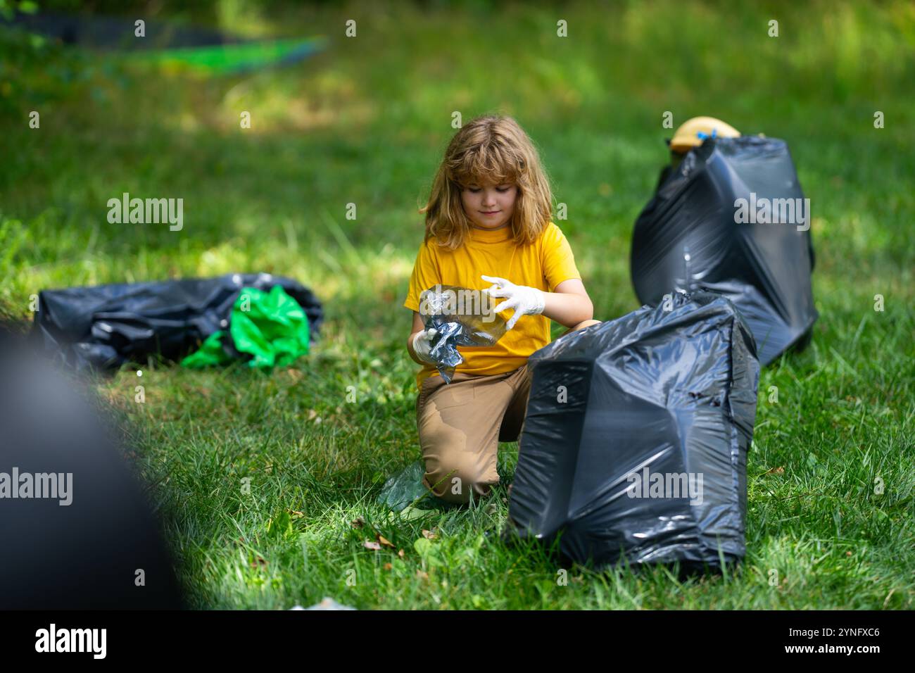 Kid in rubber gloves with trash bag clean up garbage on forest outdoor ...