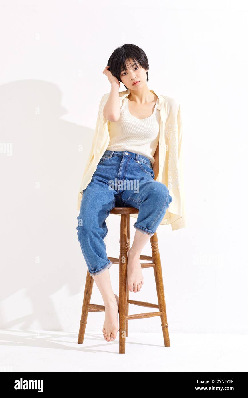 Japanese woman sitting on a stool wearing jeans Stock Photo - Alamy