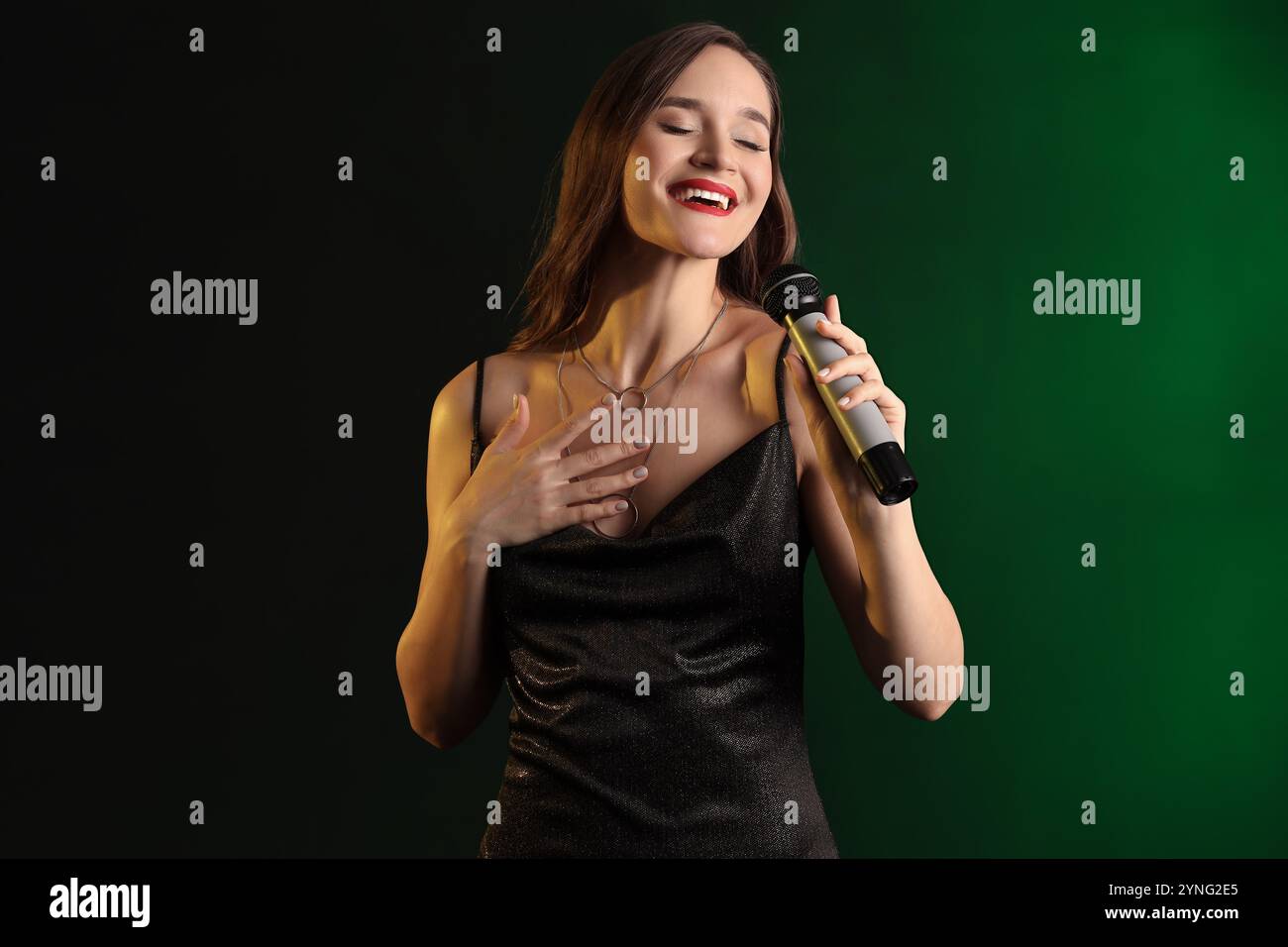 Female singer with microphone on dark green background Stock Photo - Alamy