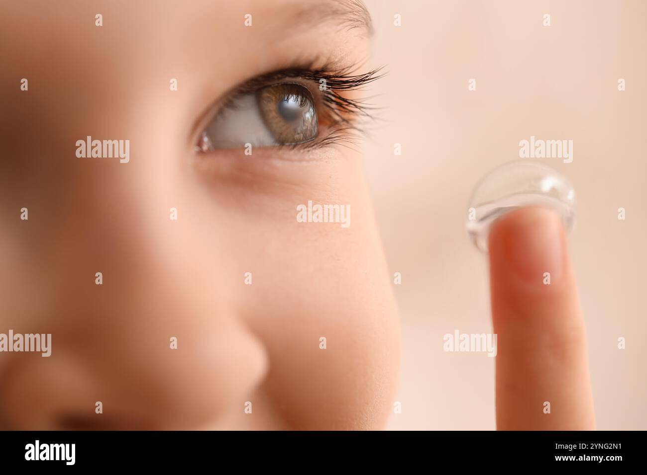 Cute little girl putting in contact lens on light background, closeup ...