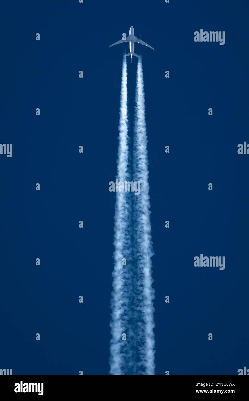 Passenger jet flies overhead with jet stream portrait view with deep ...