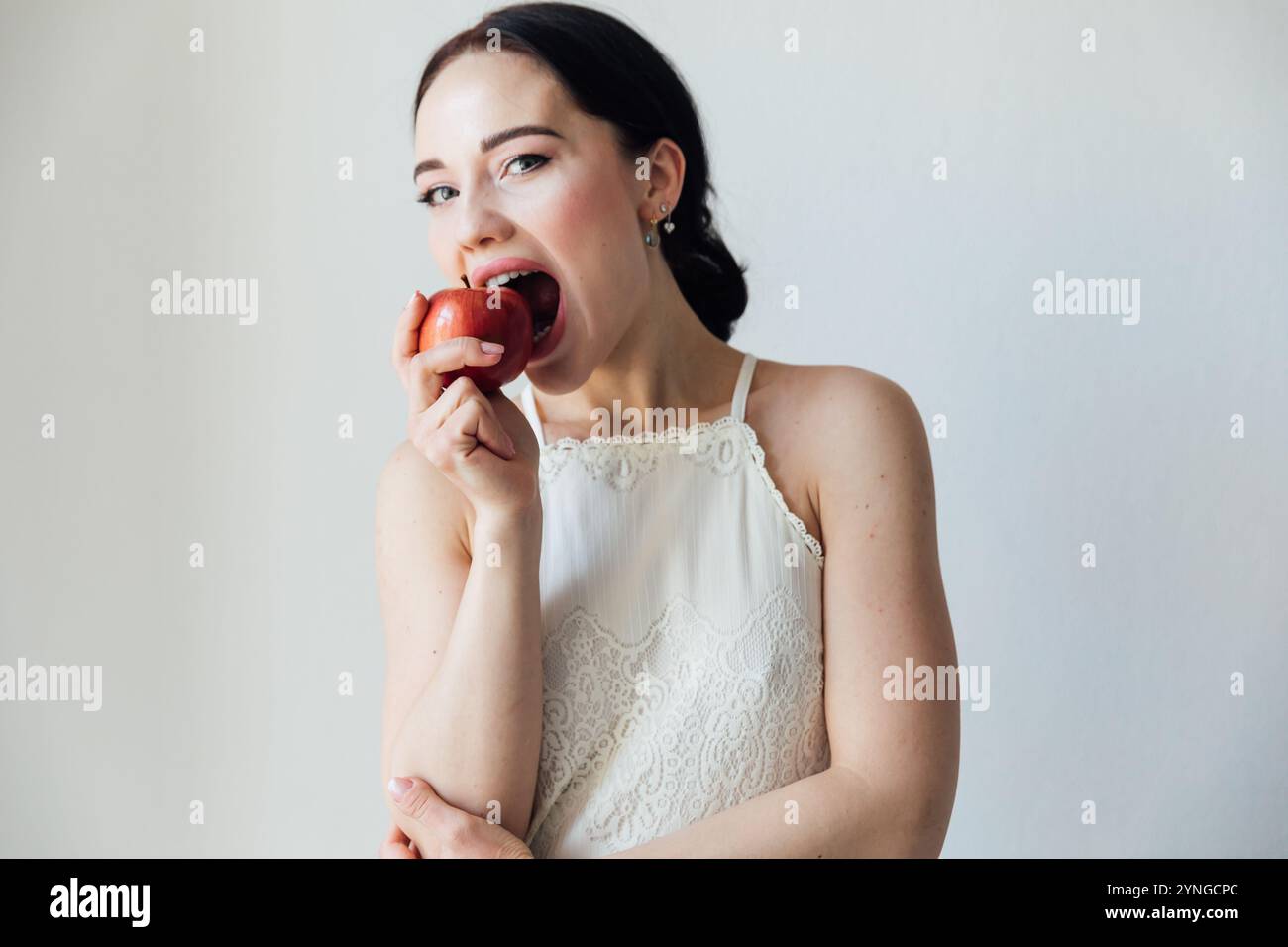 Beautiful woman eating red apple on white background Stock Photo - Alamy