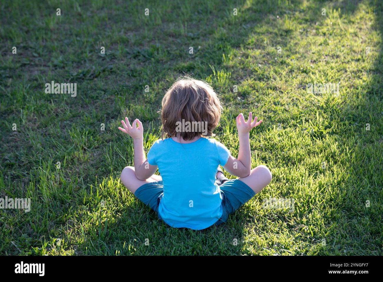 Back view of peaceful kid meditating, feeling calm positive and relaxed ...