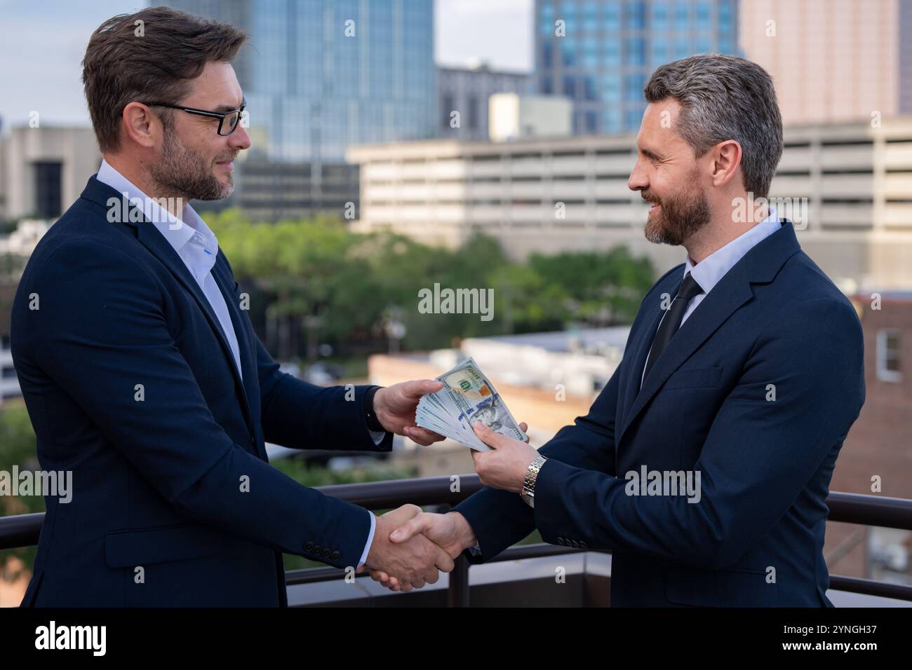 Businessmen shaking hands and receiving banknote. Businessman giving ...