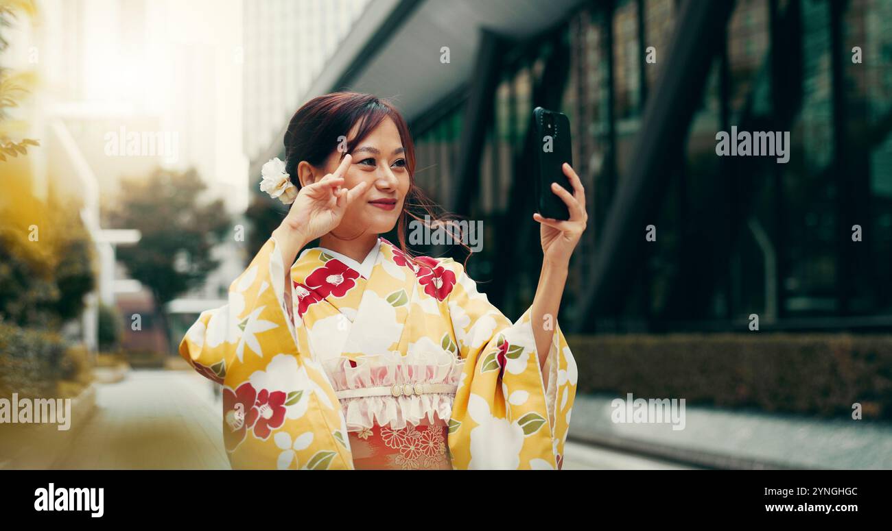 Selfie, peace sign and kimono with Japanese woman in city for profile picture, memory and ...