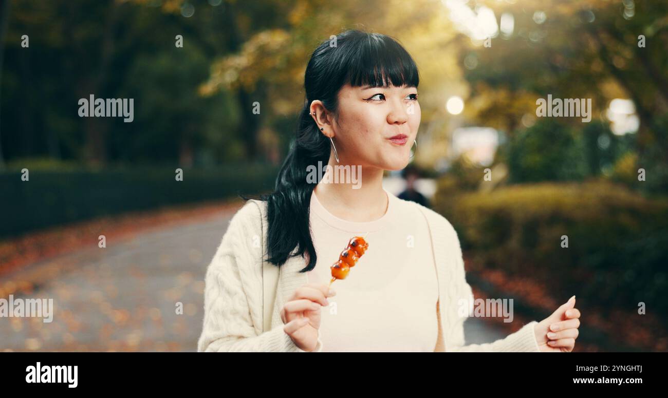 Japanese woman, walking and eating street food in park for traditional ...