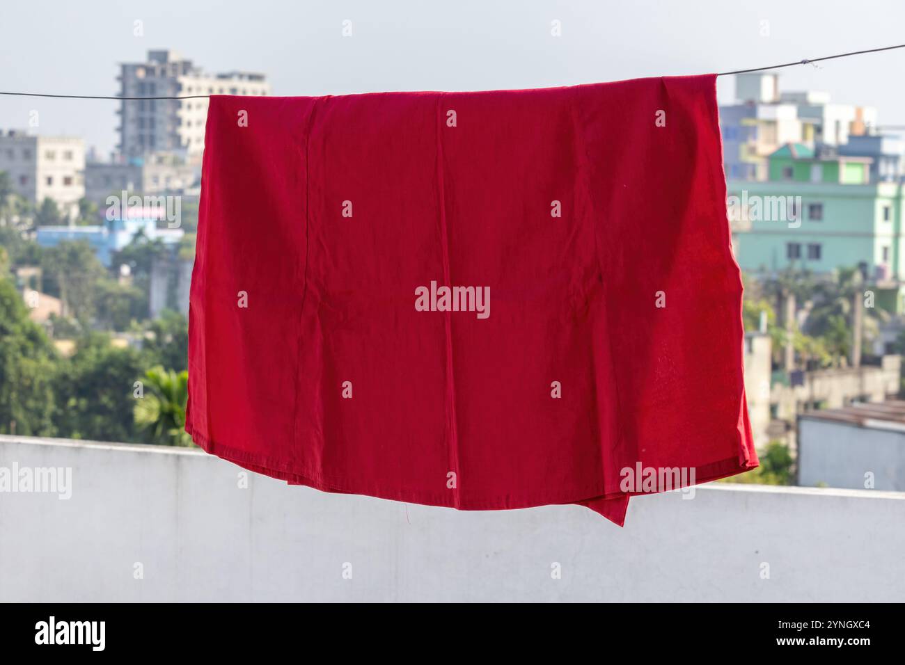 A red petticoat hanging on clothesline on rooftop, drying in the sun ...