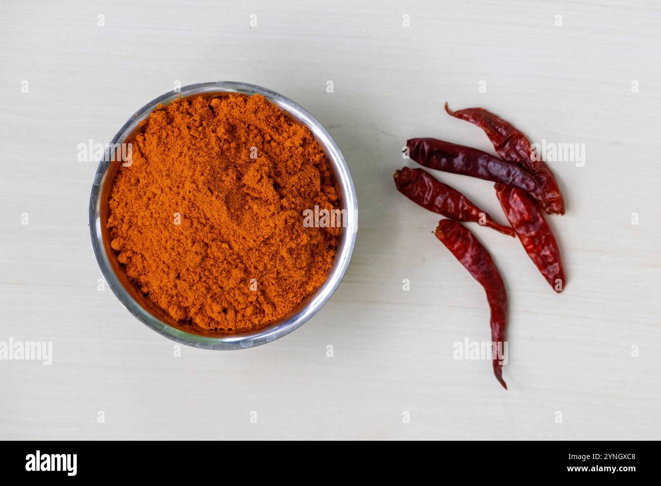 Red chili powder in a steel container, with whole dried red chilies ...