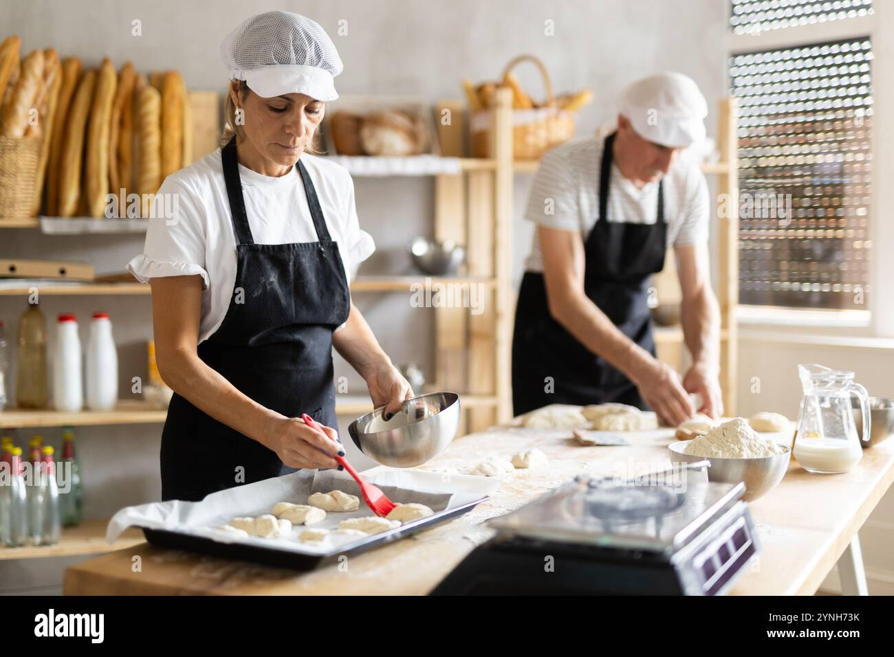 Elderly man and woman molding and greasing pieces of dough Stock Photo ...