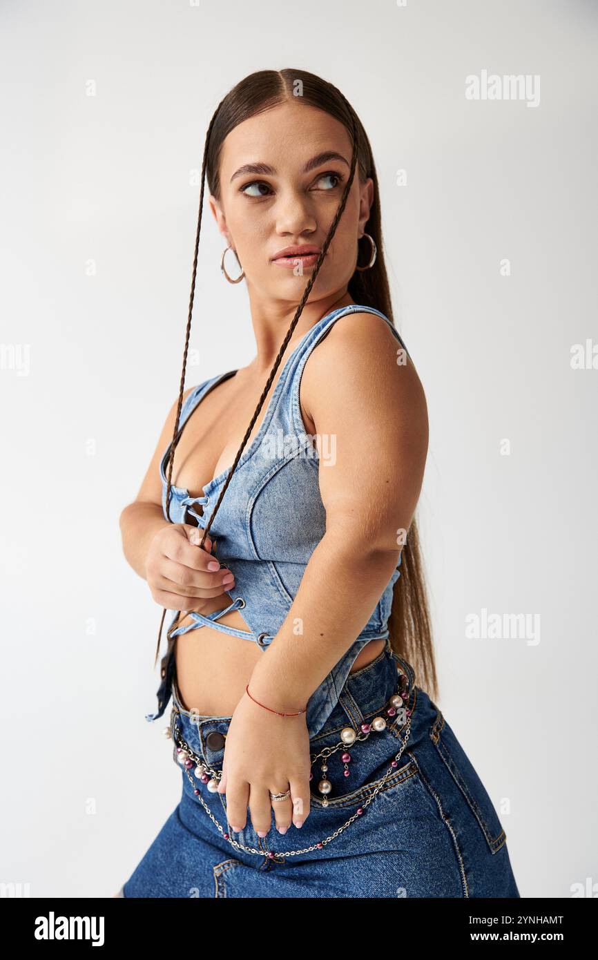 A confident young woman with short stature poses in chic denim attire, celebrating diversity ...