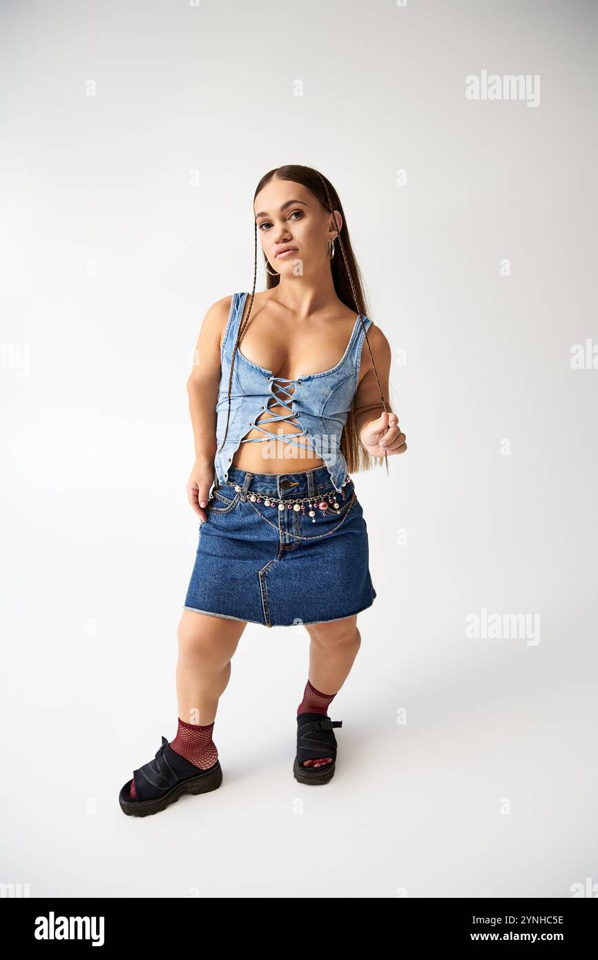 Fashionable young woman with short stature poses confidently in denim attire, celebrating ...