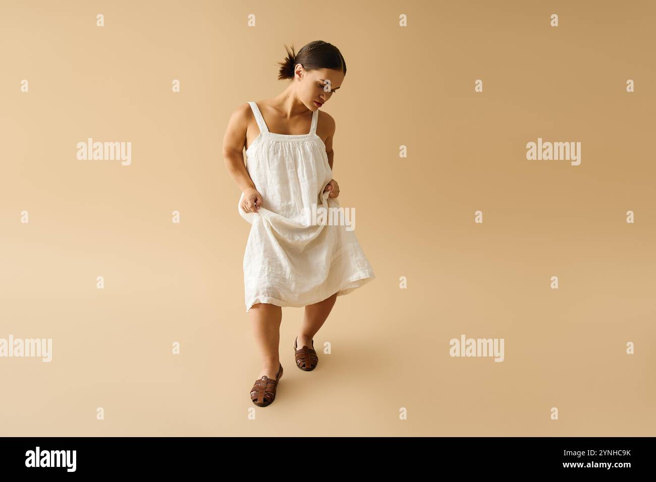 Young woman with short stature models a stylish white dress in a warm ...