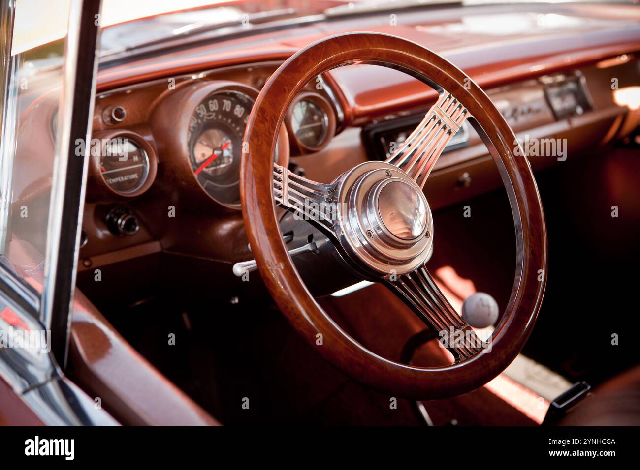 The brown wooden steering wheel and dasboard of a classic American car ...