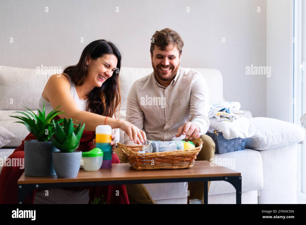 Happy pregnant couple preparing baby things at home with natural light ...