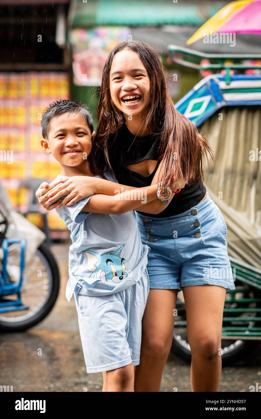 A pretty long Filipina girl hugs her young friend for a cute pose ...