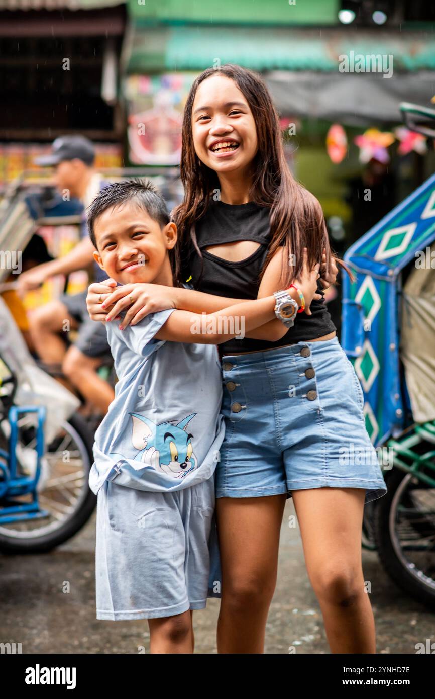 A pretty long Filipina girl hugs her young friend for a cute pose ...