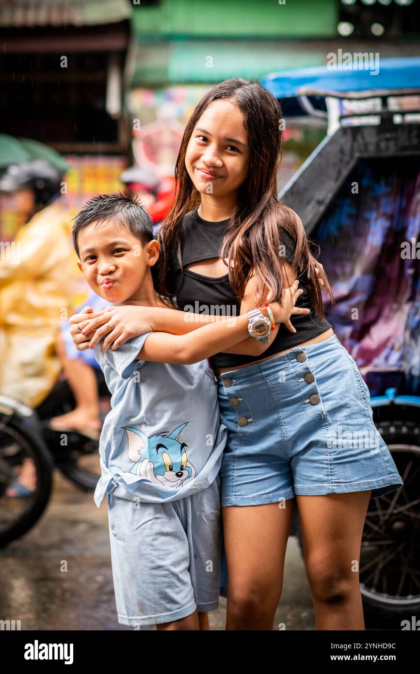 A pretty long Filipina girl hugs her young friend for a cute pose ...