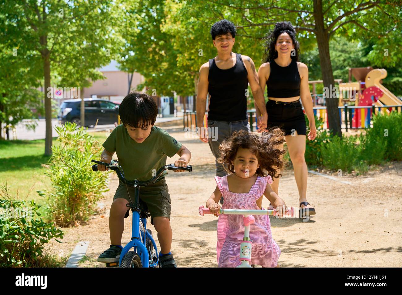 children riding bikes in the park with their parents Stock Photo - Alamy