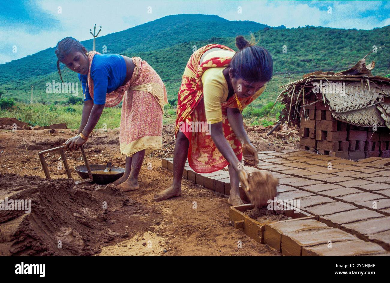 India, Rajasthan. Women put clay in a mold to make bricks for house ...