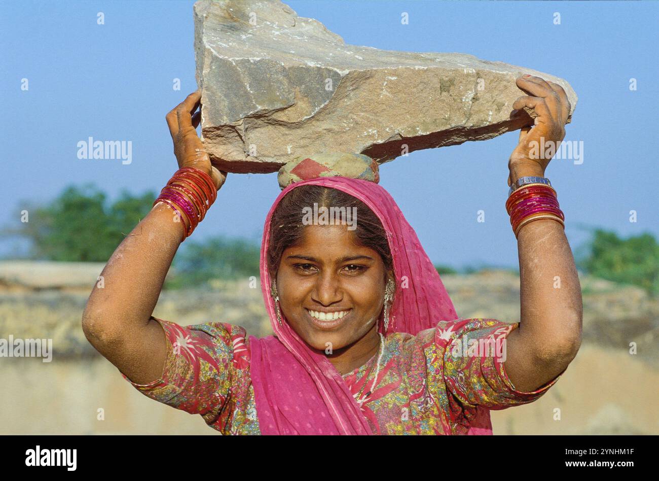 India, Rajasthan, during road construction a woman carries chunk of ...