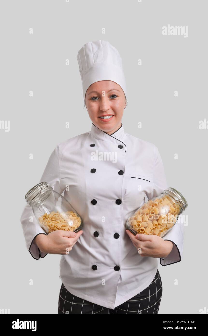 Female chef holding two glass jars filled with different types of pasta ...