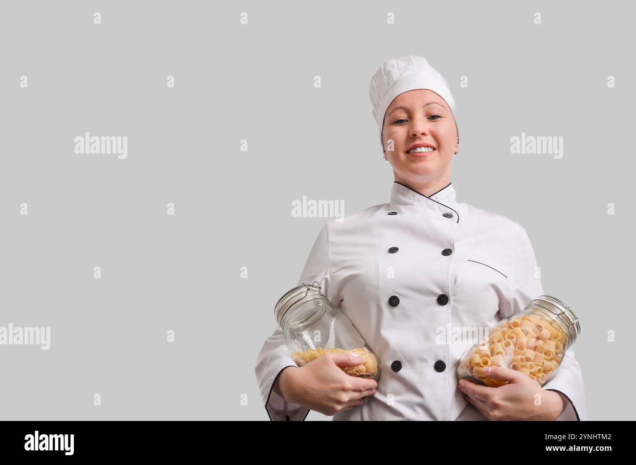 Female chef in white uniform holding two glass jars filled with ...