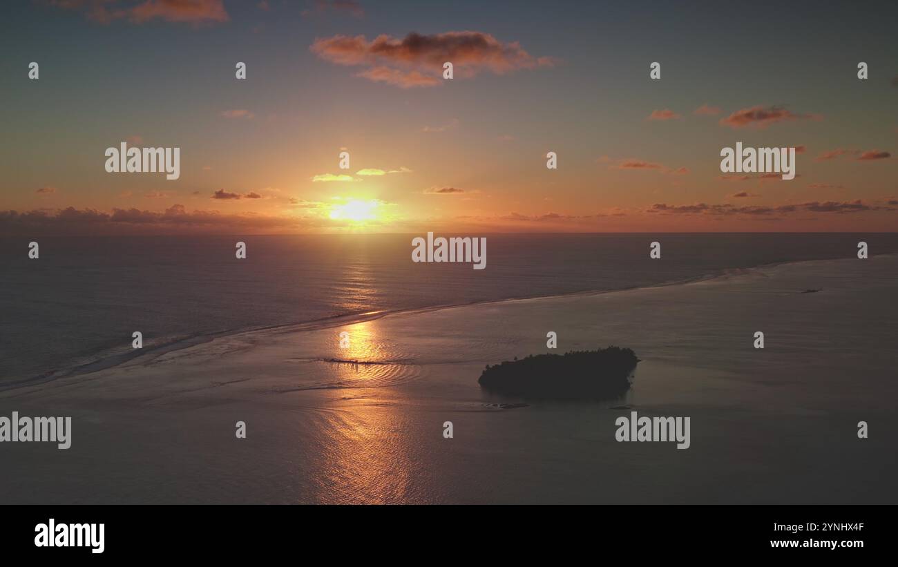 Golden hour sunlight reflects on vast ocean Tikehau island, creating a ...
