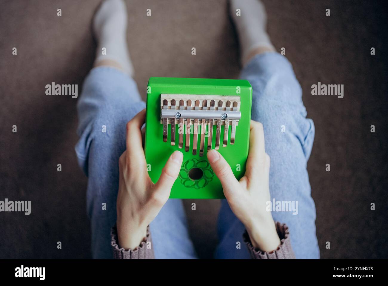 Woman playing a green kalimba, a traditional african musical instrument ...