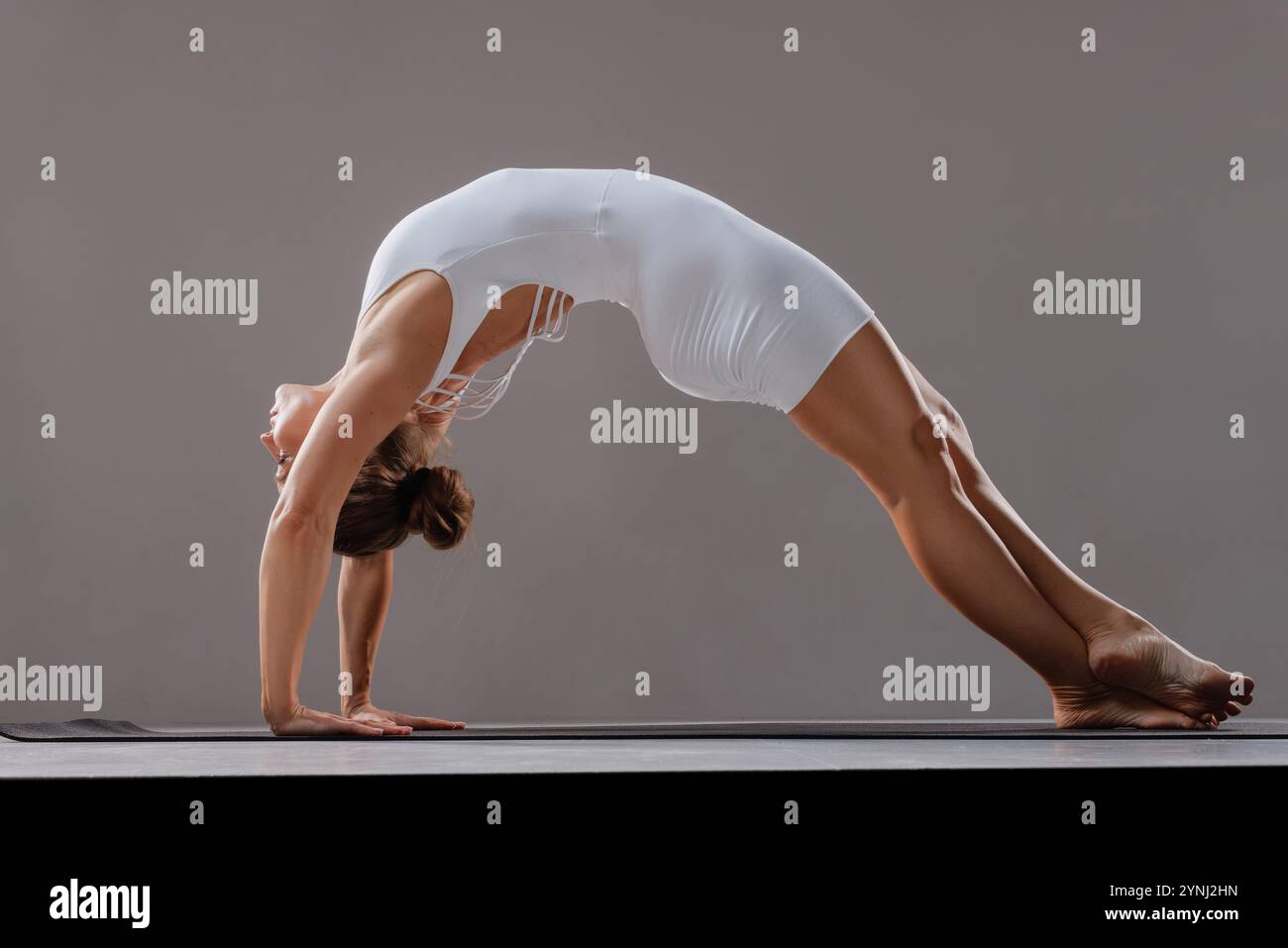 Woman doing yoga pose, arching her back in bridge pose. on yoga mat ...