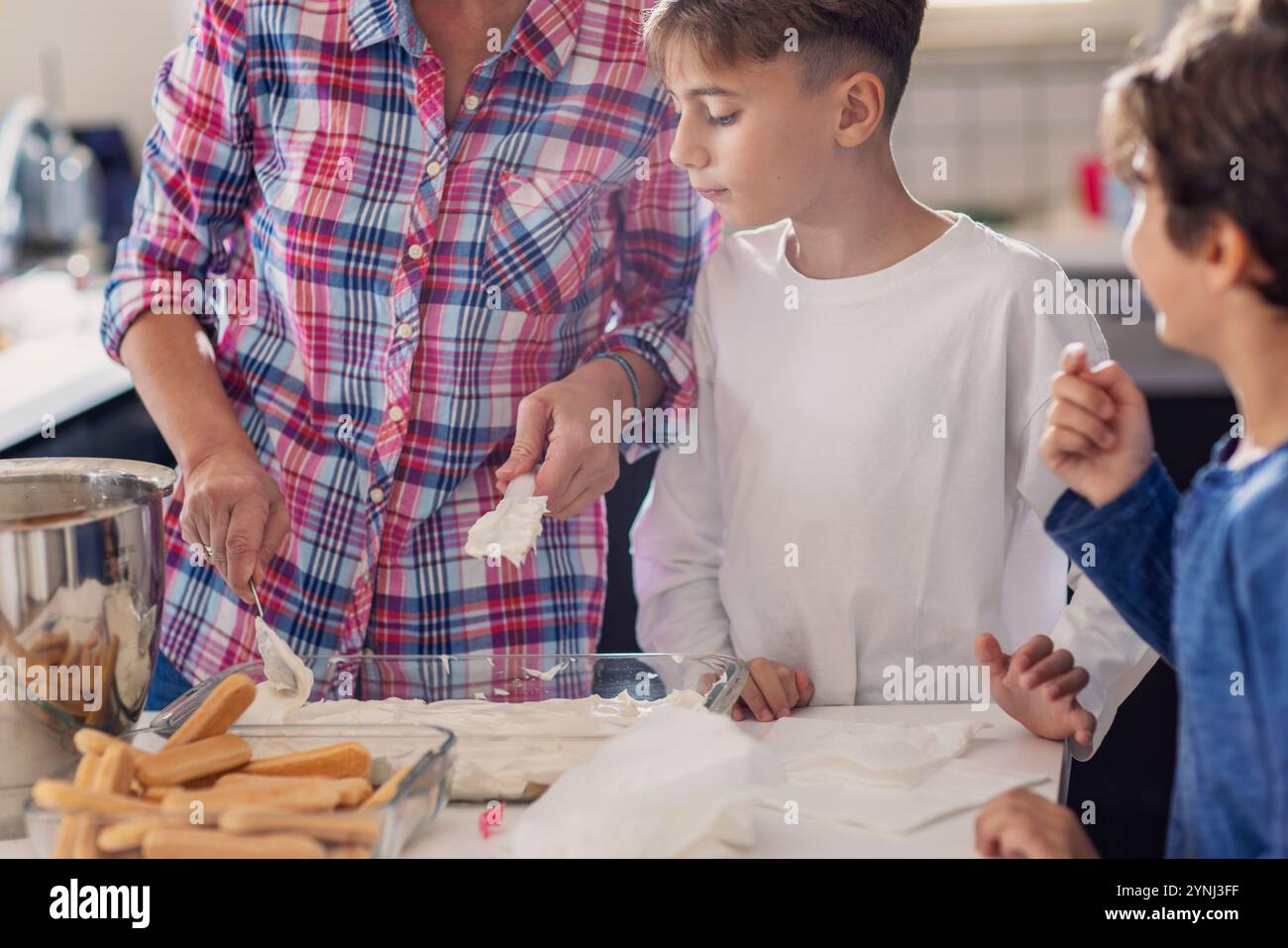 Children engage in a baking activity while an adult demonstrates how to ...