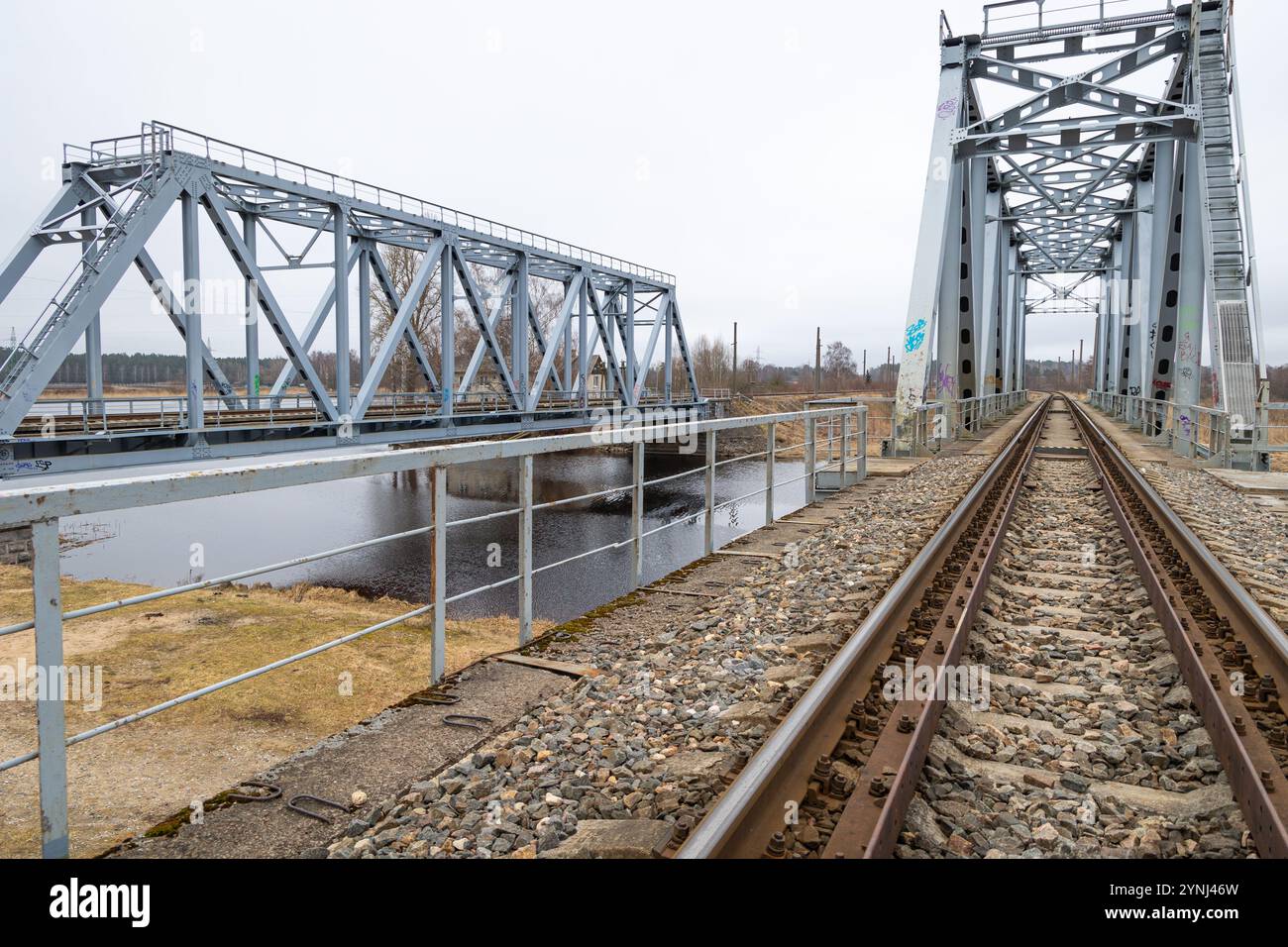 Two parallel metal truss bridges with railway tracks over the river ...