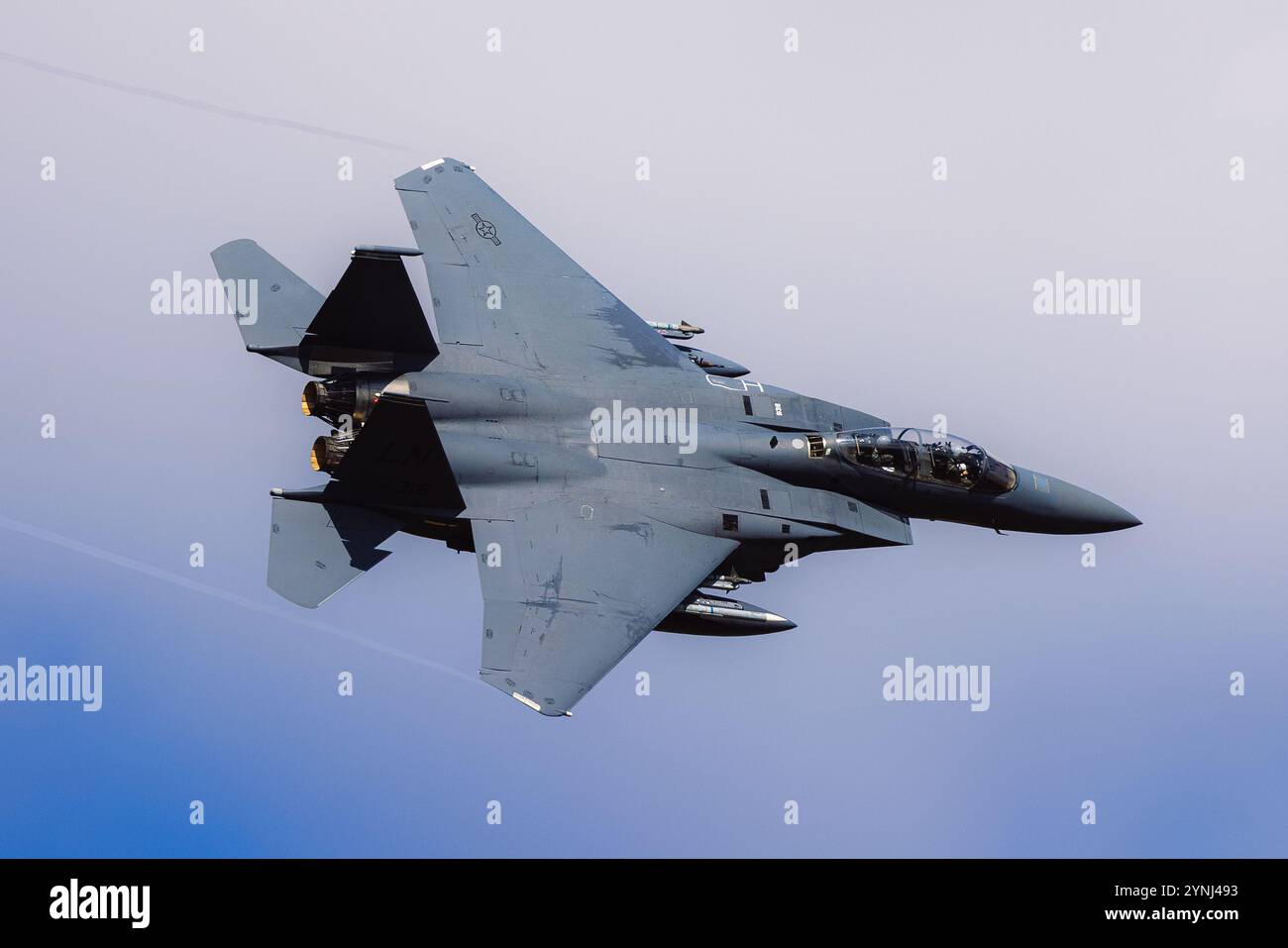 An F-15 Eagle fighter jet soars through the blue sky, showcasing its ...