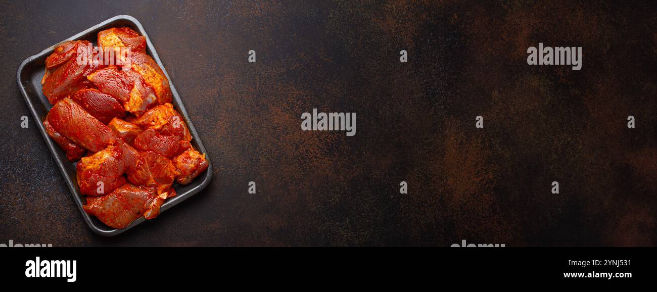Raw uncooked chopped pieces of pork marinade with seasonings in black ...