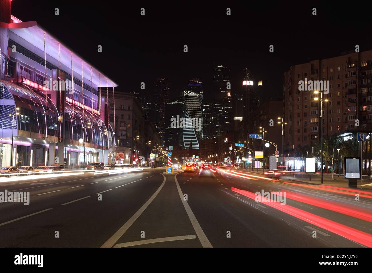Night photo of the urban city street with busy highway and neon lights ...