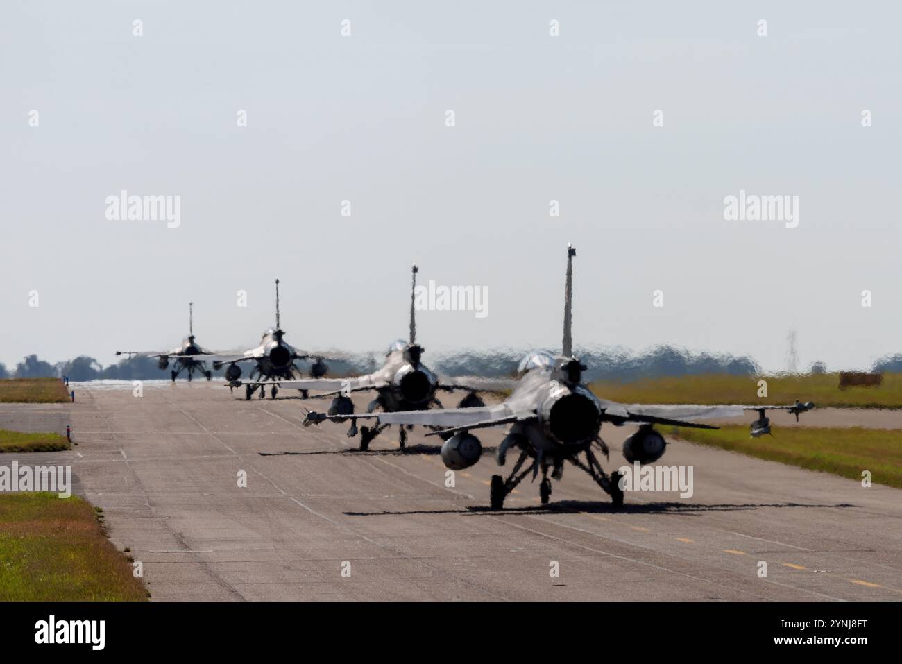 A line of fighter jets taxi down the runway in perfect formation ...