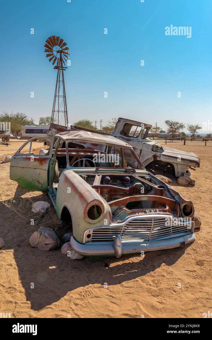 Car and truck wrecks with a windmill in the Namib desert in Solitaire ...