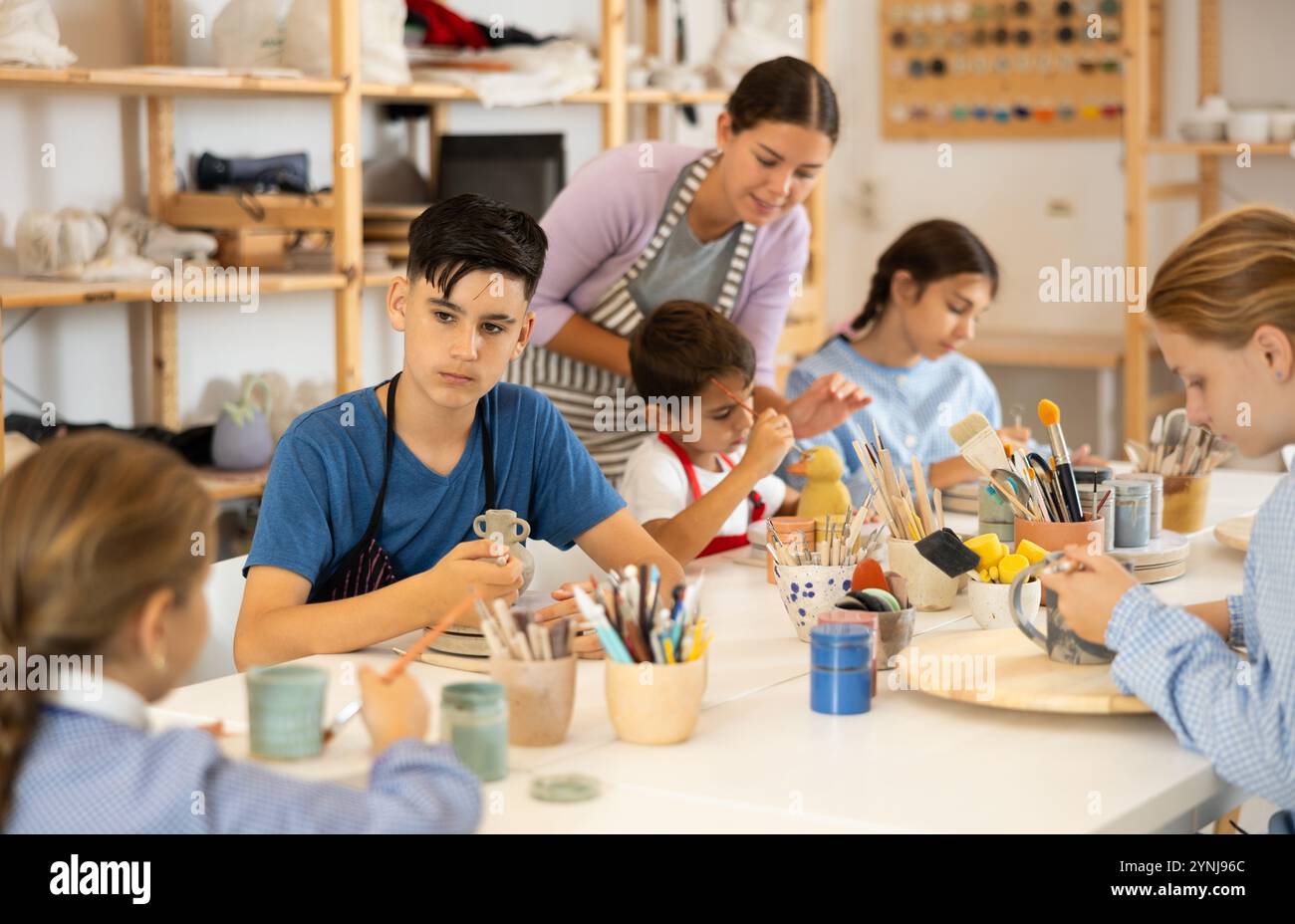 Teenage boy looking at a group mate while working with ceramica Stock ...