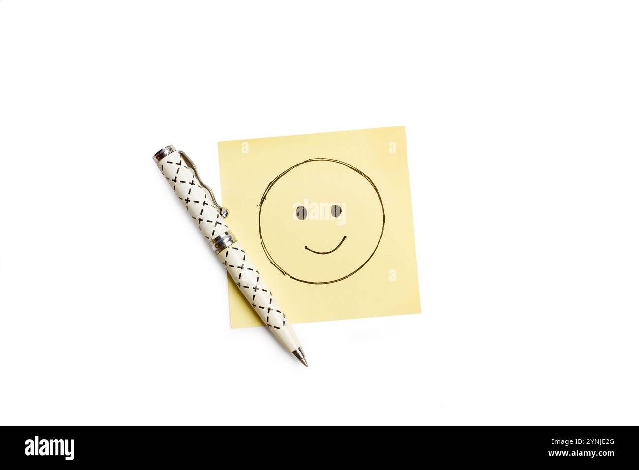 A smiley face drawn on a yellow sticky paper and a pen on a white ...