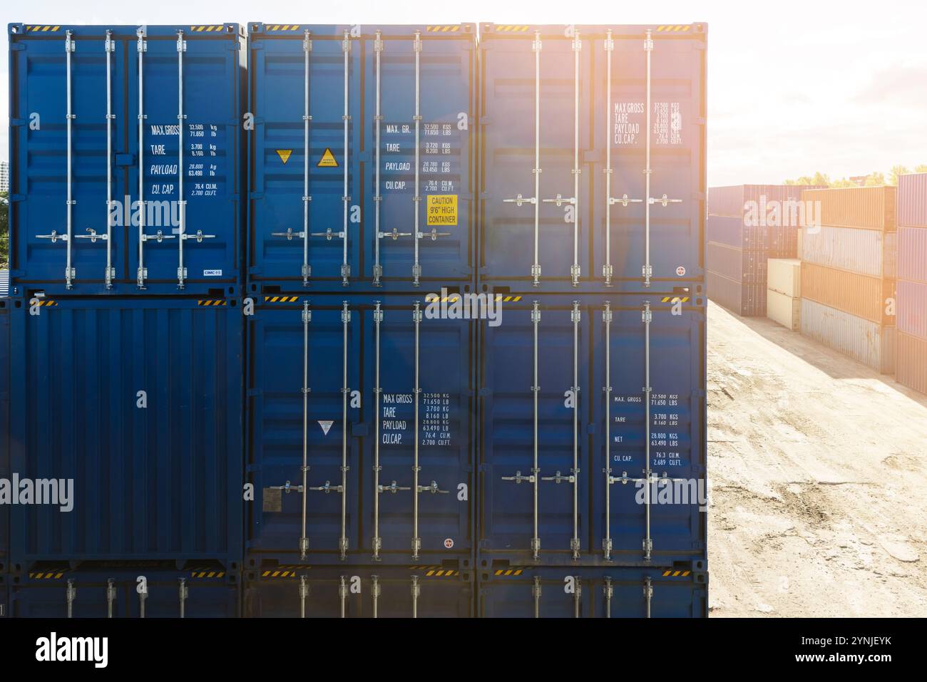 Port storage area with stacked blue cargo containers on a sunny day ...