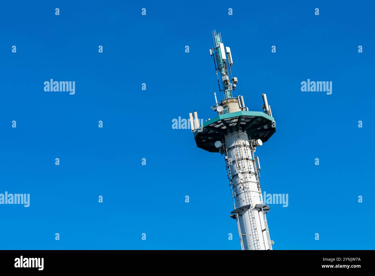 Tall communications tower rises into the blue sky, showcasing antennas and equipment crucial for ...
