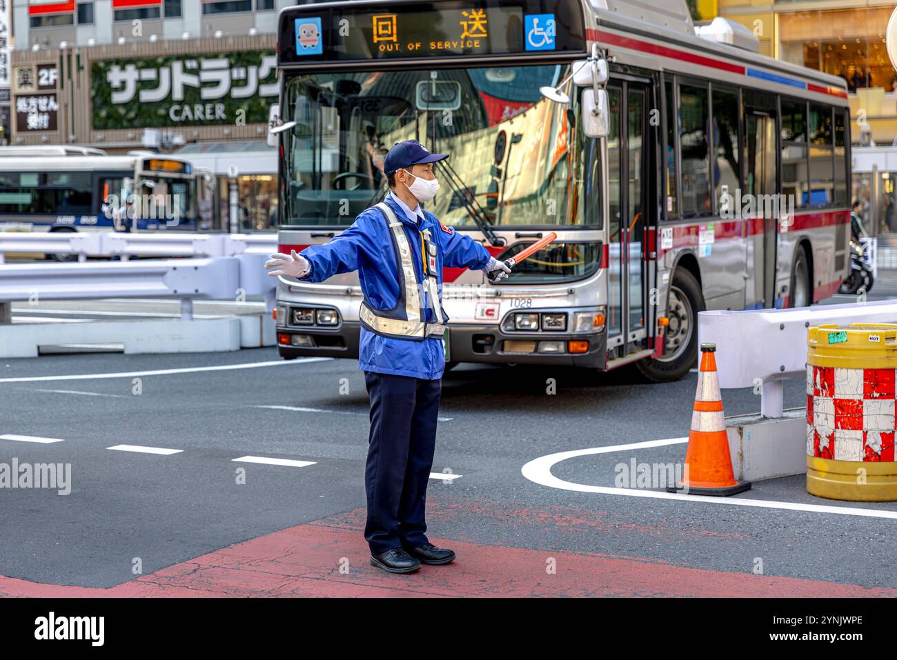 Japanese security guard wearing face mask directing traffic in tokyo ...